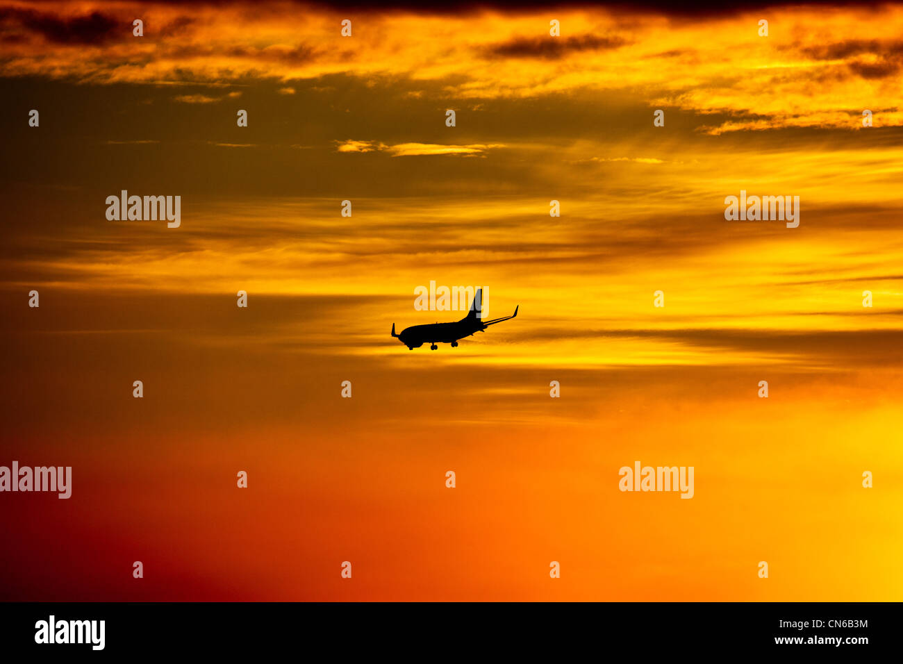 Plane flying in sunset Stock Photo - Alamy