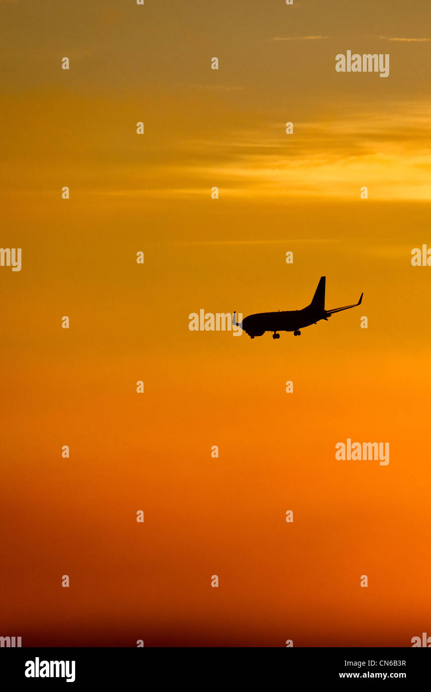 Plane flying in sunset Stock Photo - Alamy