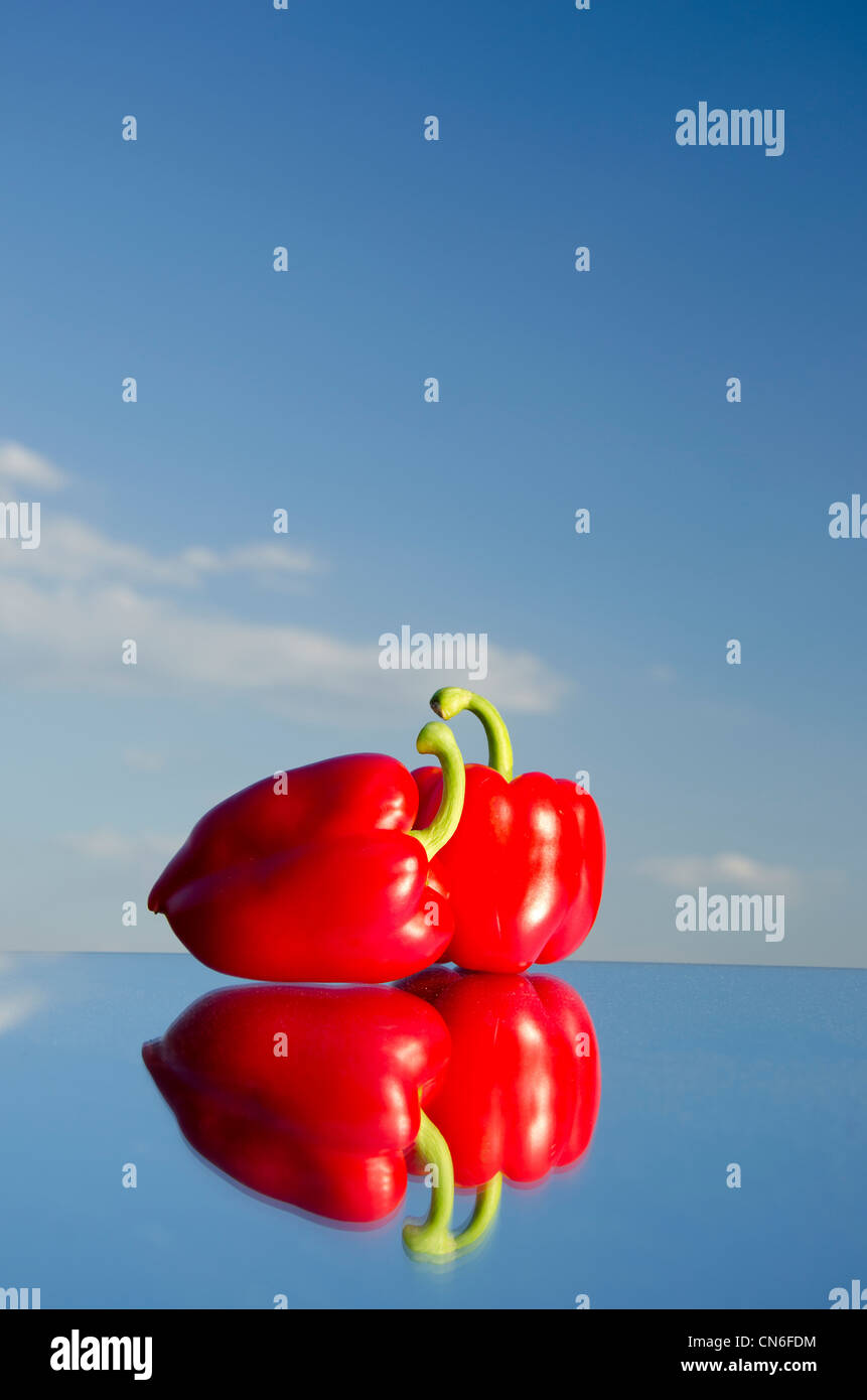 two red peppers on mirror and blue sky Stock Photo - Alamy