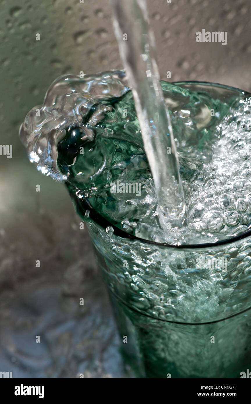 Tumbler glasses overflowing with bubbling water Stock Photo - Alamy