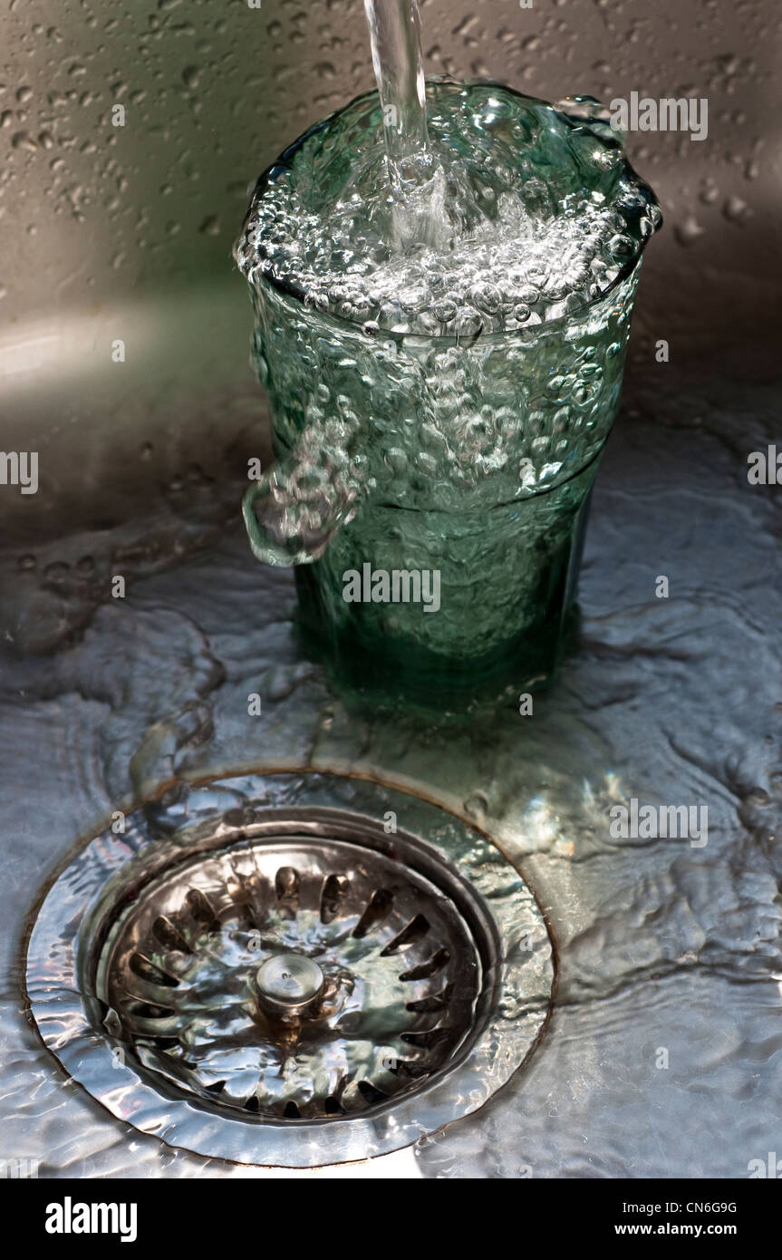 Tumbler glass overflowing with bubbling water Stock Photo - Alamy