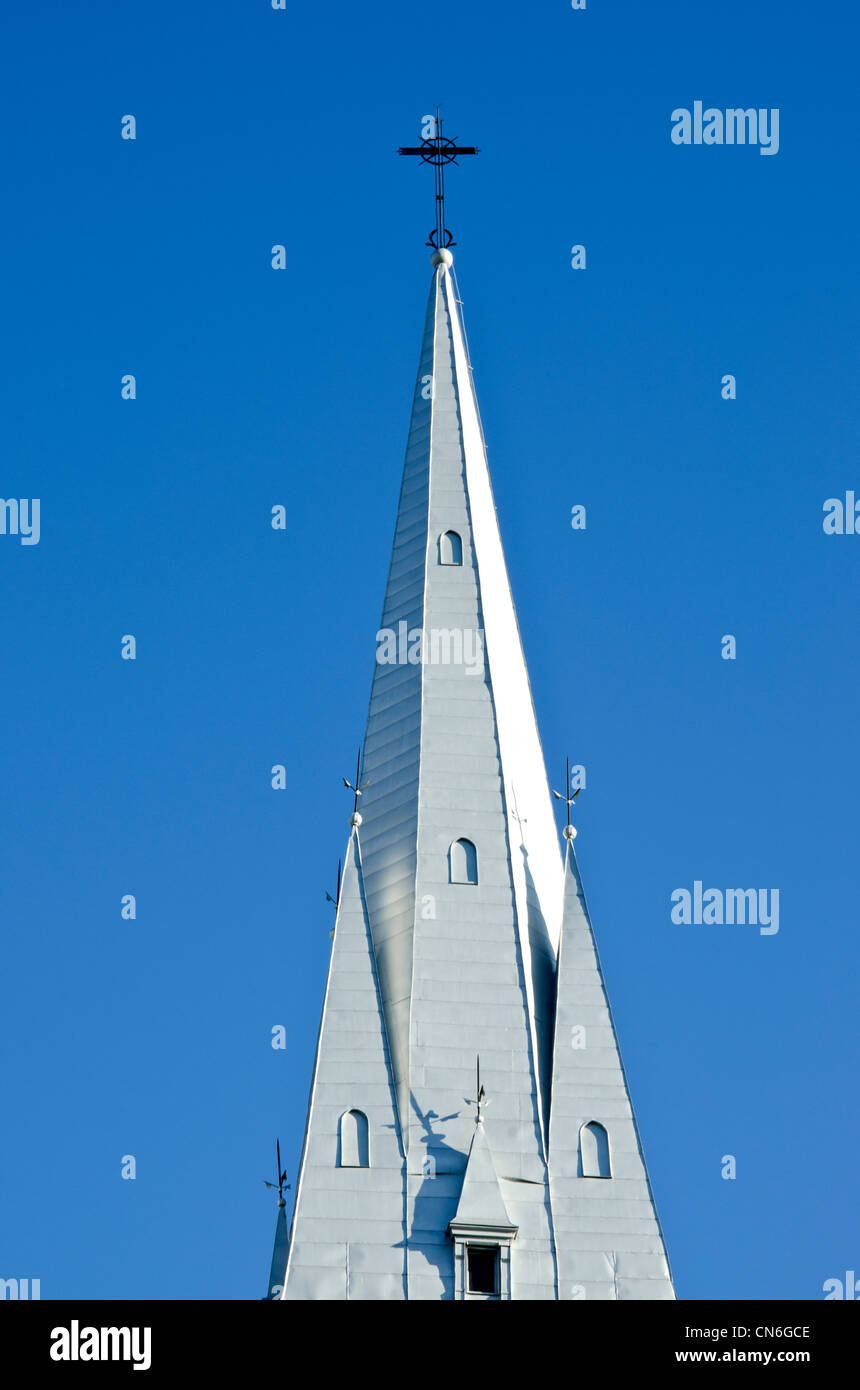 Church tower with cross on top on background of blue sky. Religious tin ...