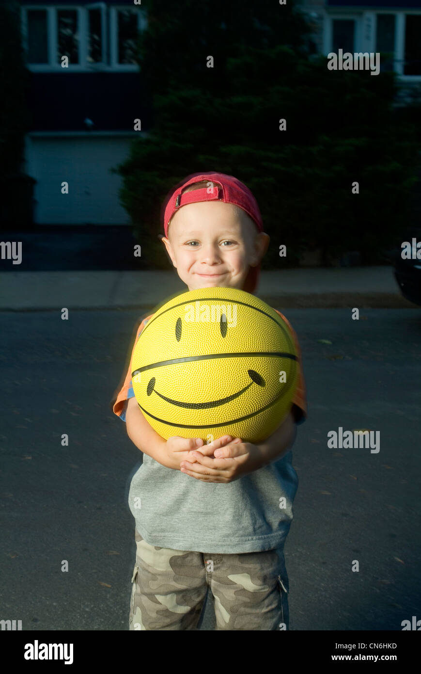 Portrait of a Little Boy Holding a Basketball with a Smiley Face on it ...