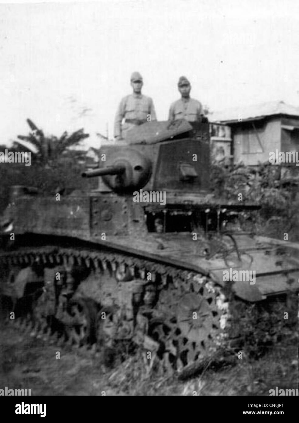 Two Japanese Army soldiers pose with a captured U.S. M3 Stuart tank ...