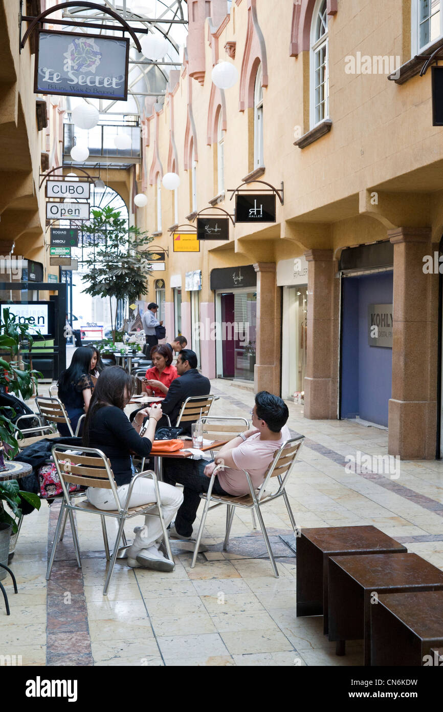 people sitting at cafe tables in block through skylit European style ...