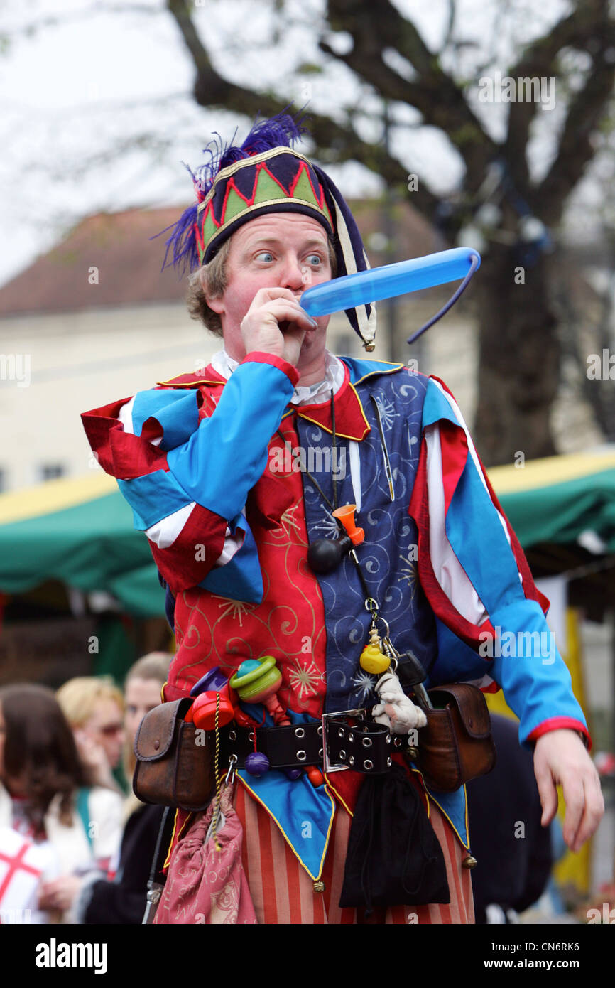 Street entertainer dressed as a jester blowing up balloons Stock Photo ...