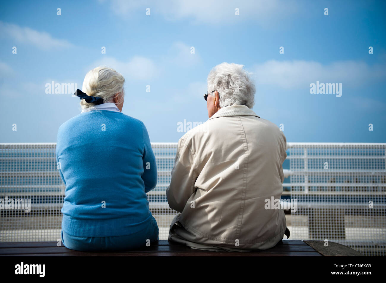 Rear view of two elderly retired women sitting on a bench on ...