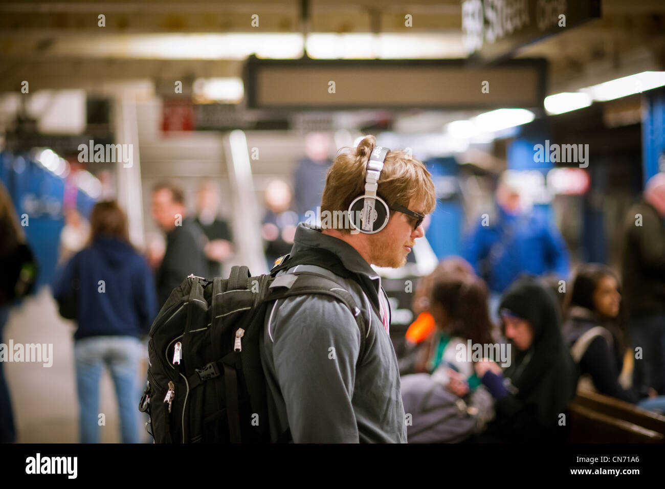 A music listener wears his over the ear headphones on a subway platform ...