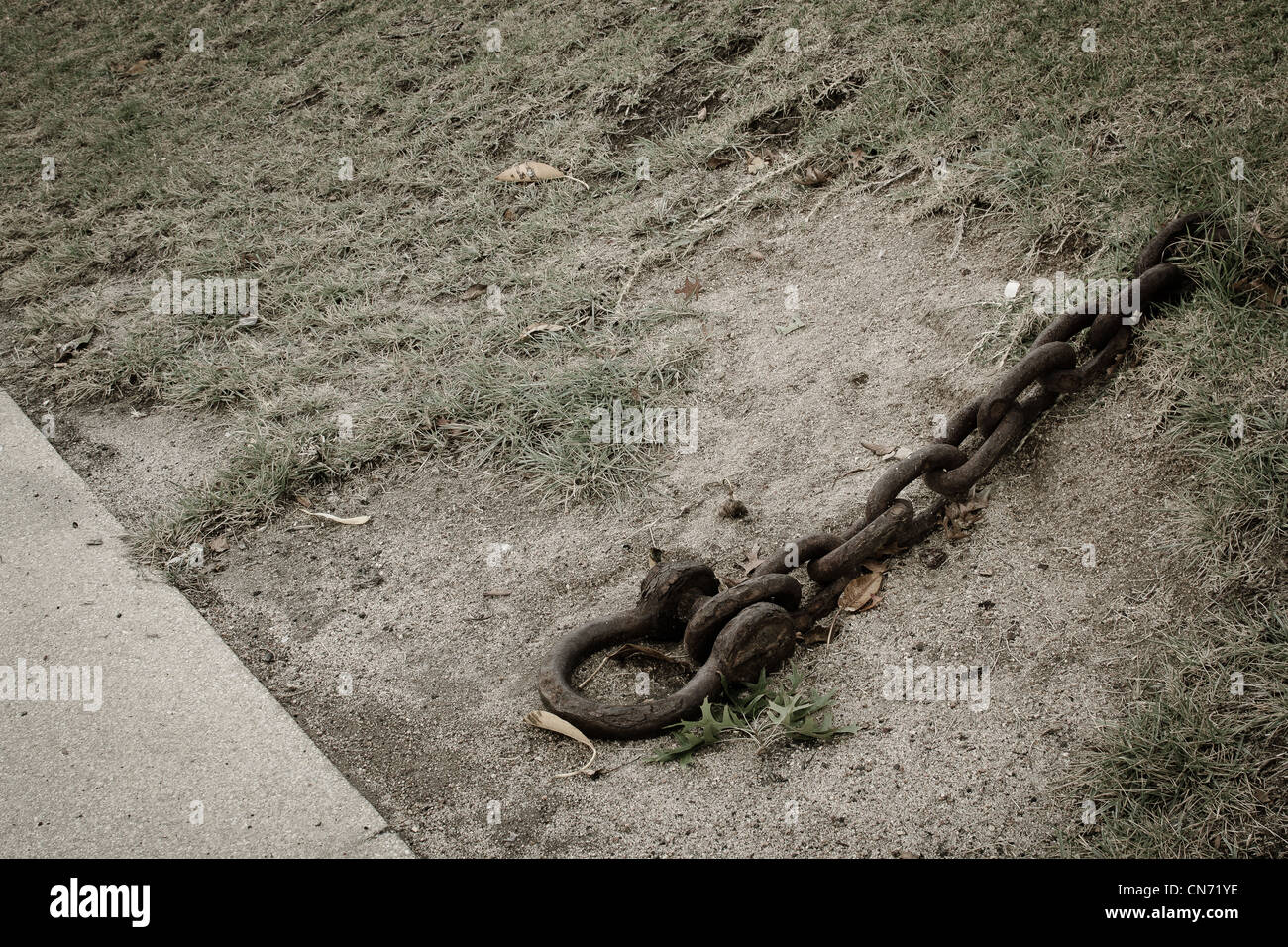 A large rusting metal chain hammered into the ground Stock Photo - Alamy