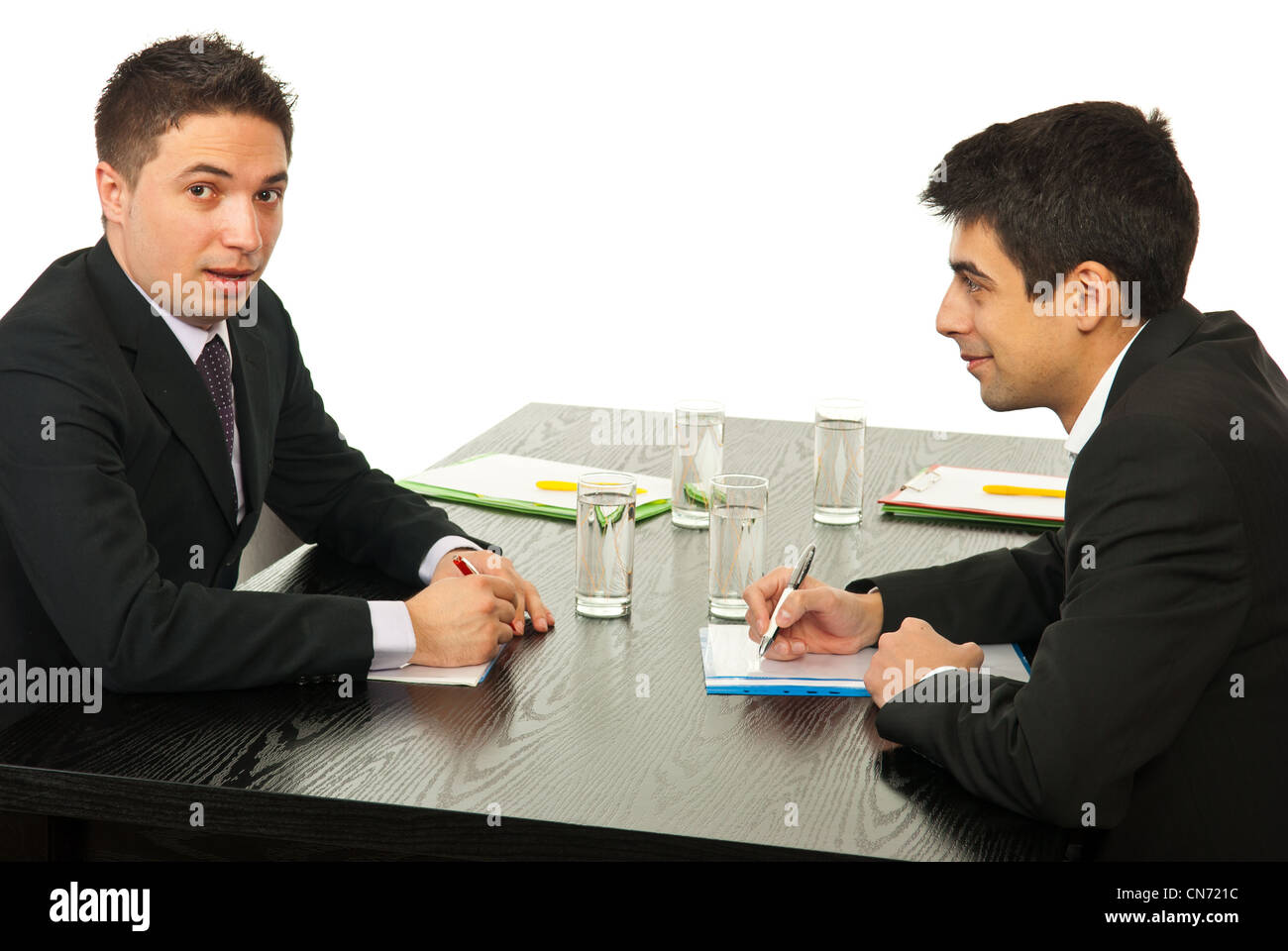 Two young business men talking at meeting together and sitting on ...