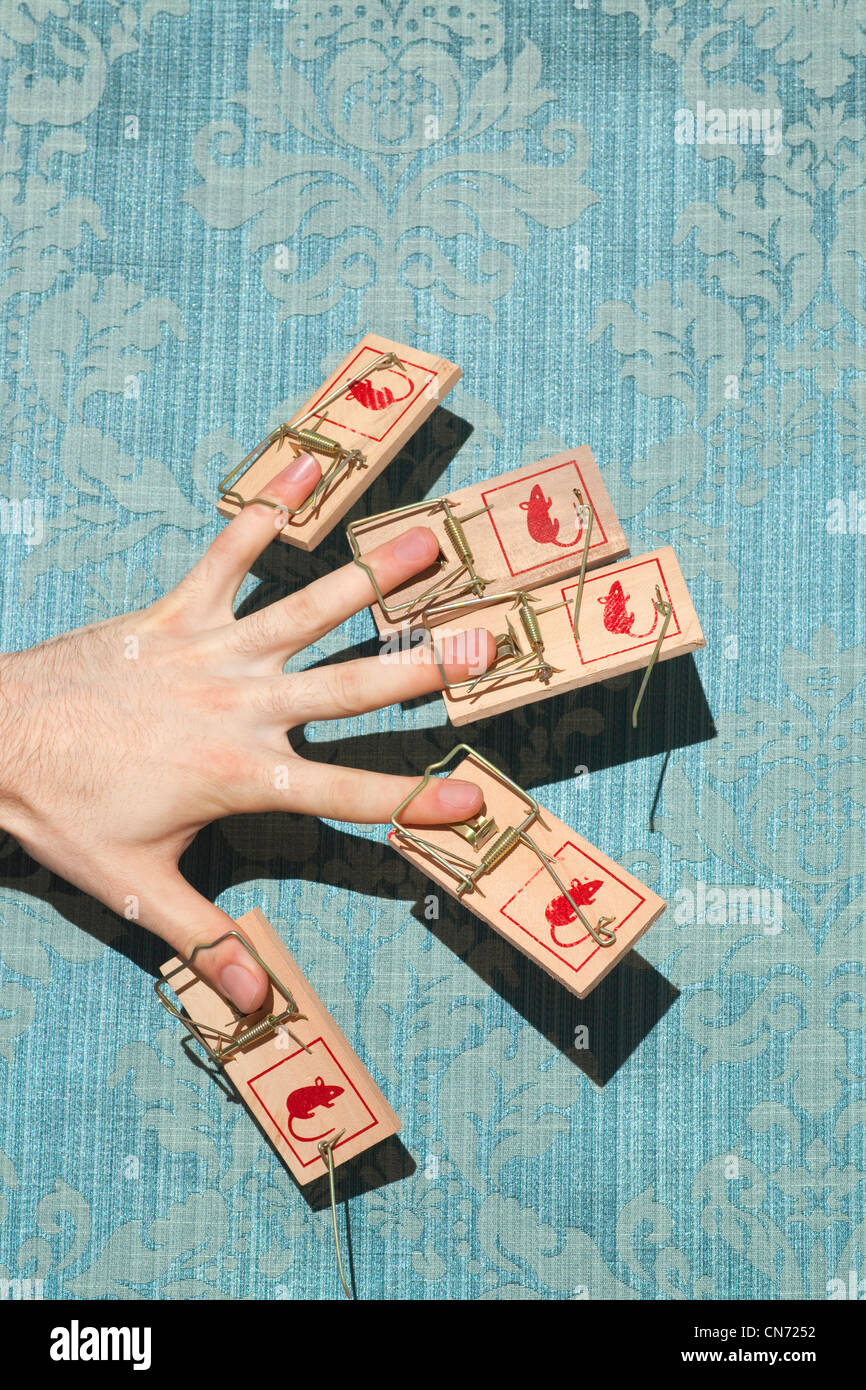 Portrait of hand being trapped by mouse traps with wallpaper background ...