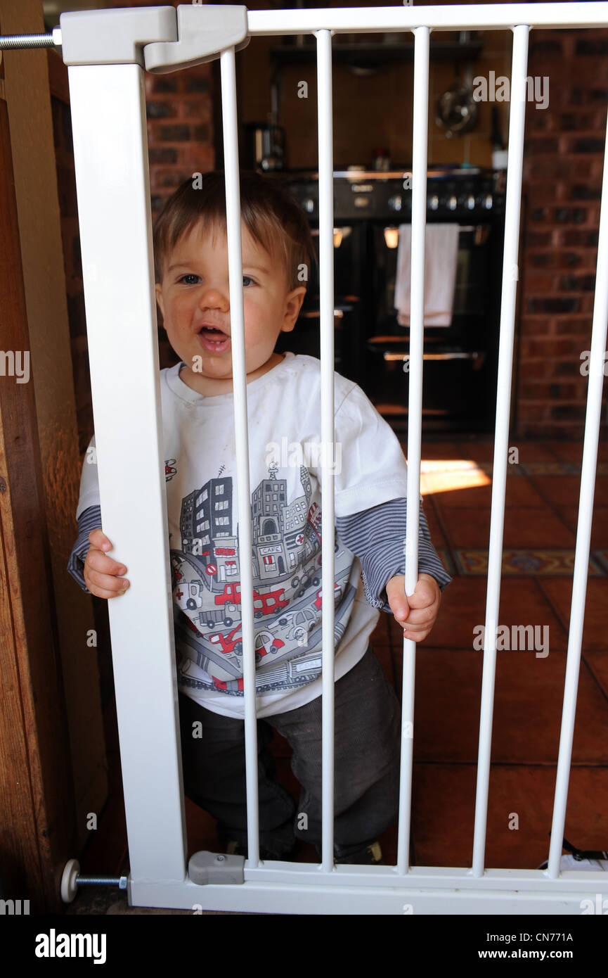 Toddler behind child safety gate Stock Photo - Alamy