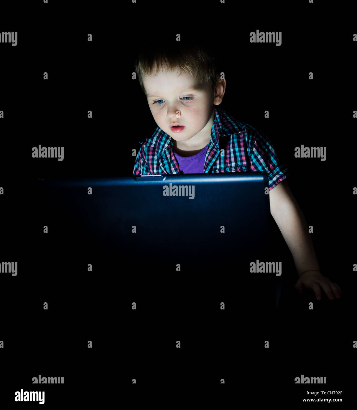Little kid using laptop by night Stock Photo - Alamy