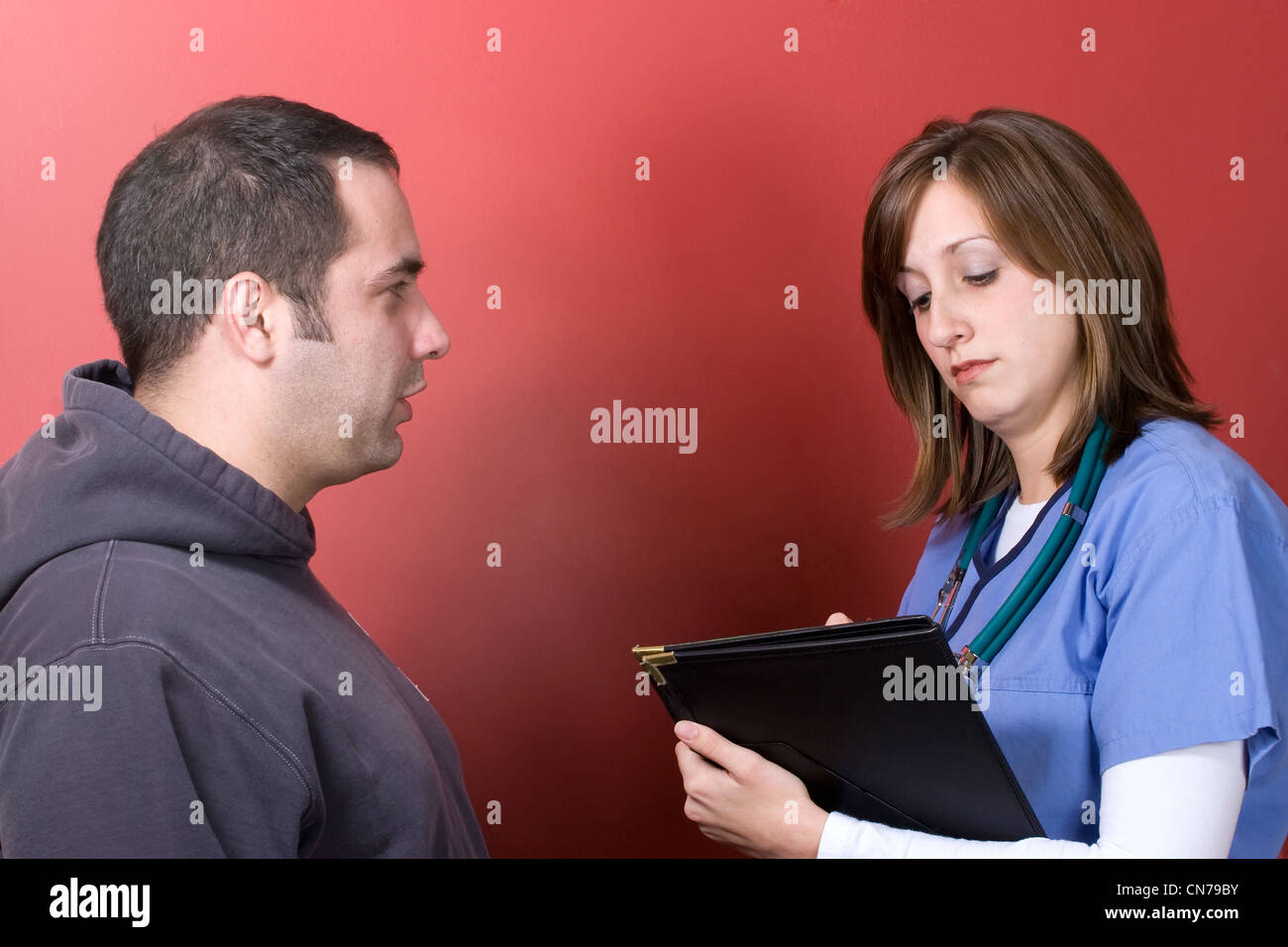A young nurse talks to a concerned patient during his visit Stock Photo ...