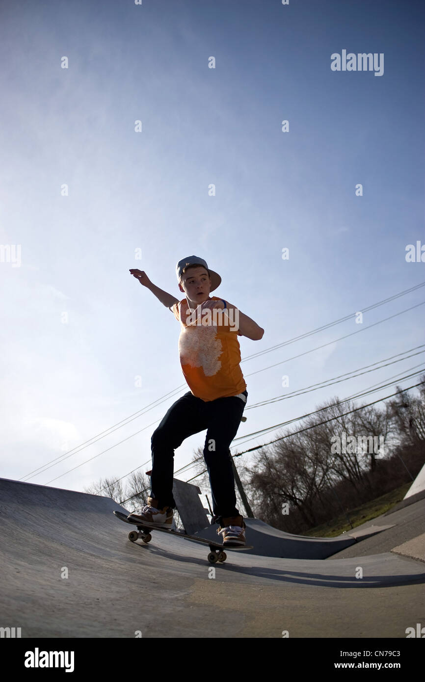 Portrait of a young skateboarder skating down a ramp at the skate park ...