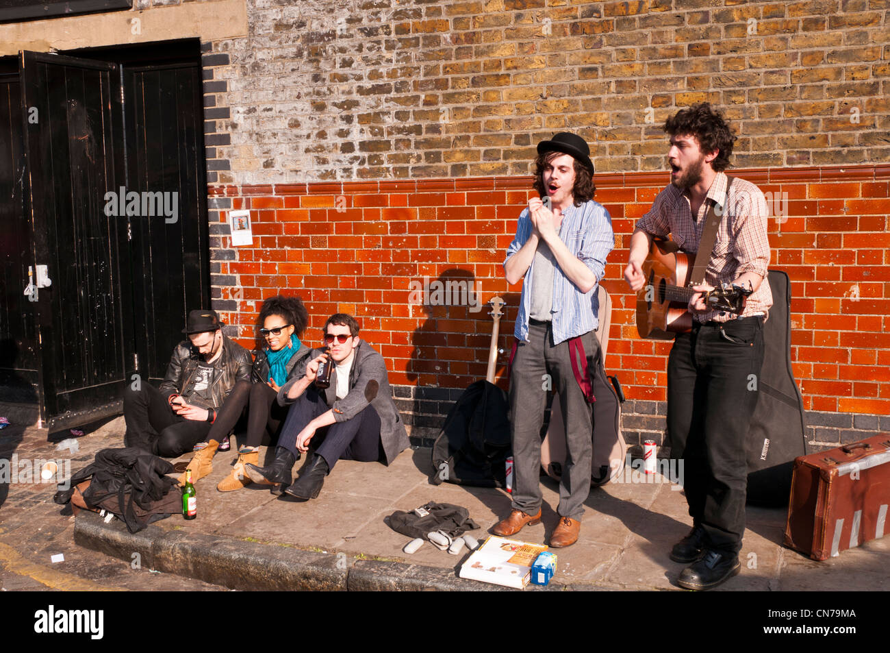 Two young buskers playing guitar and singing in the street, East London ...