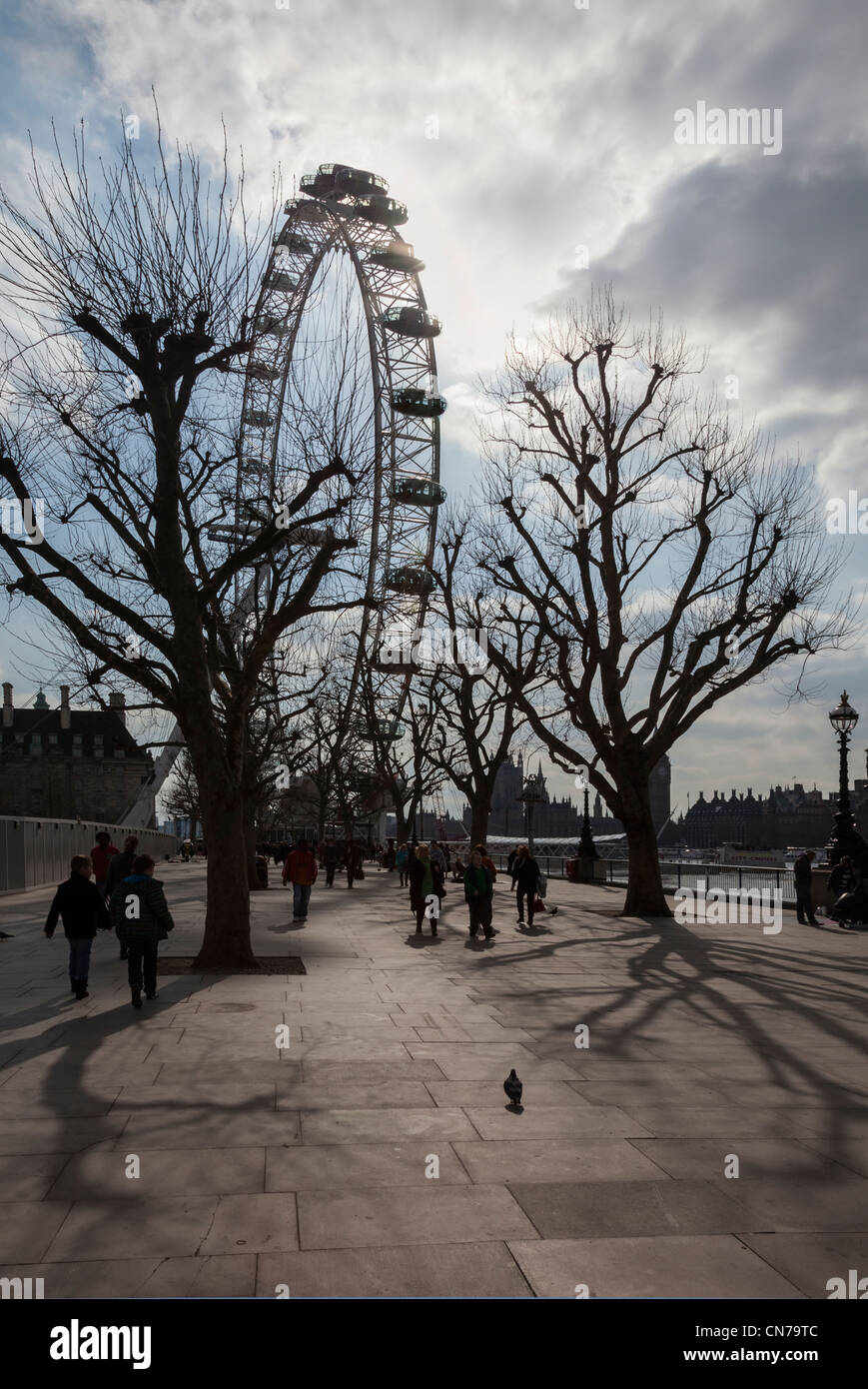 The London Eye from the pavement on the south bank looking into the sun ...