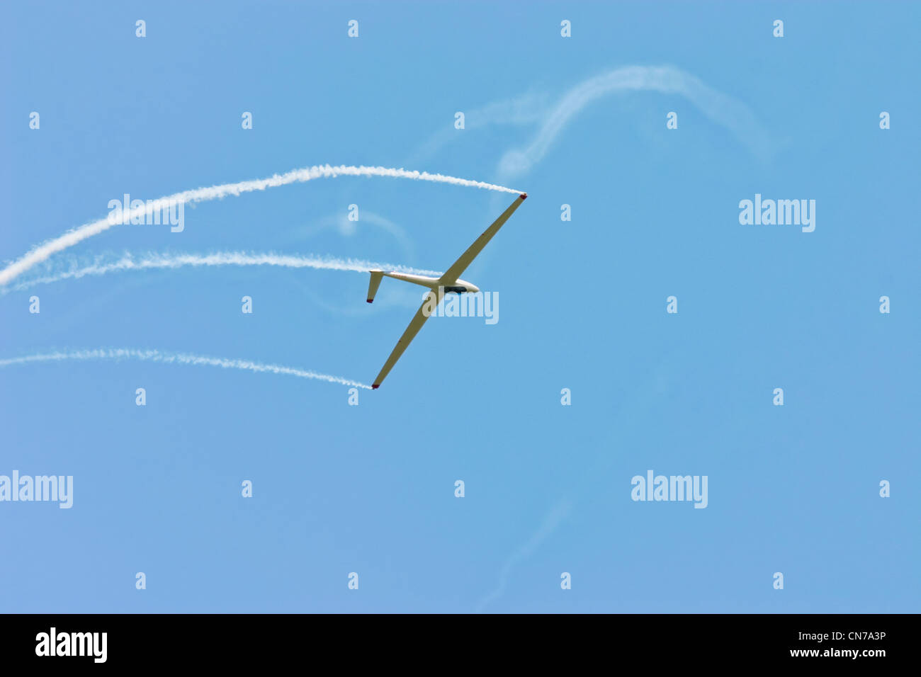 Glider flying aerobatic stunts with smoke against blue sky Stock Photo ...