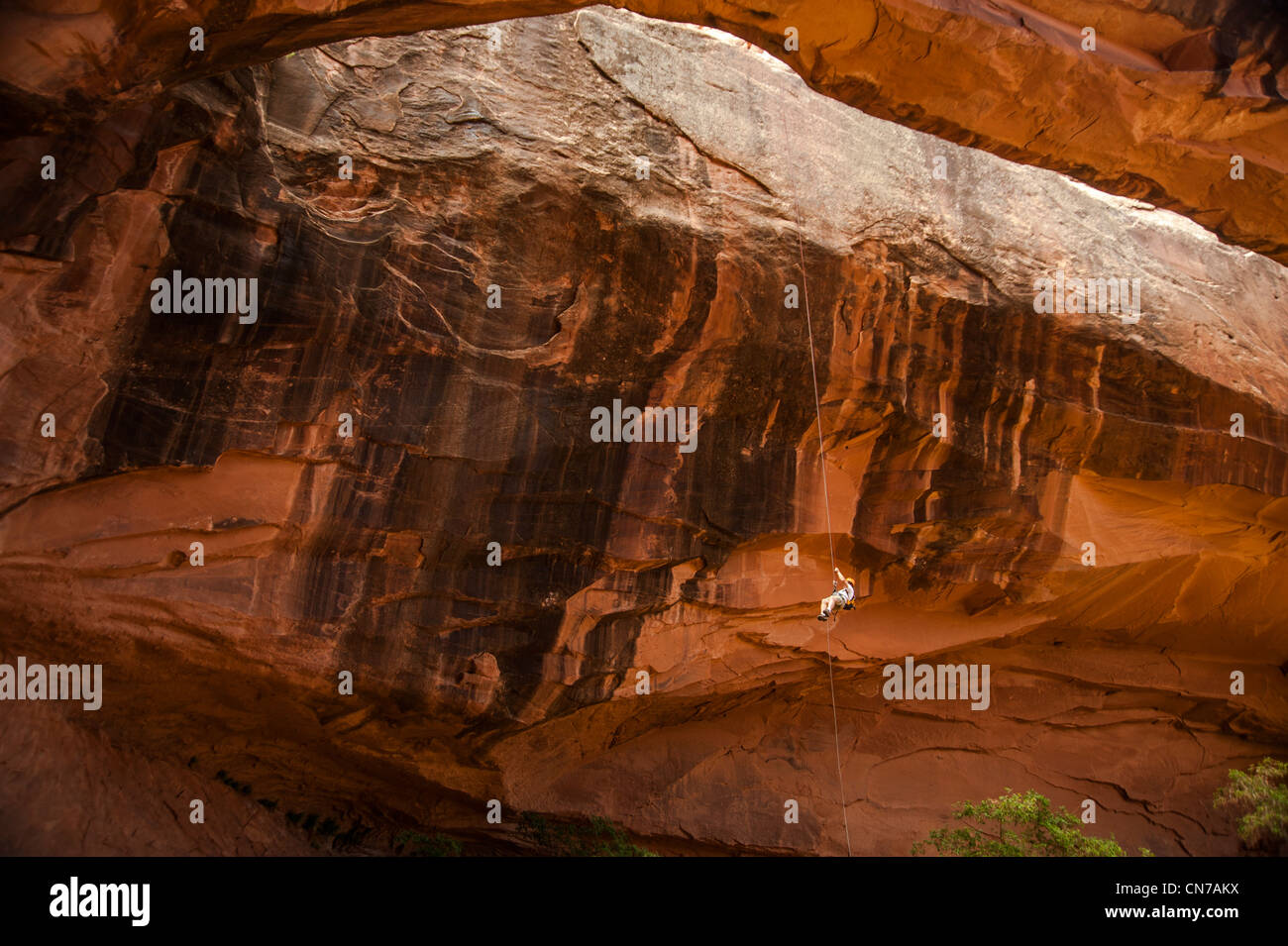 Rock climber rappelling down orange cliff in Utah Stock Photo - Alamy