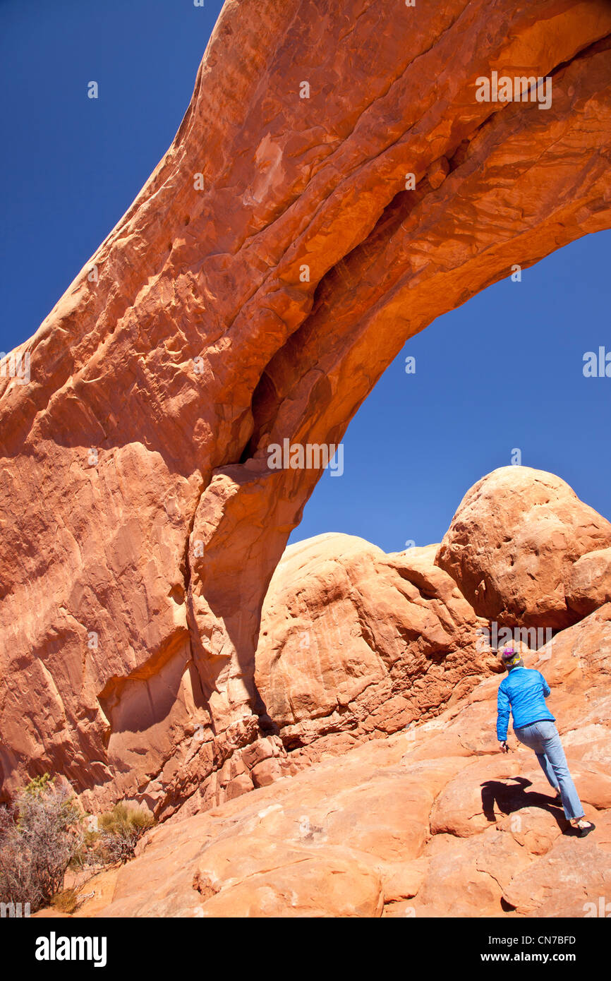 Lone hiker walks below the North Window Arch in Arches National Park ...