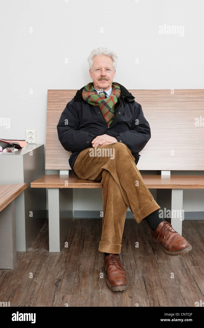 elderly man, sitting patiently in the waiting room of a medical ...