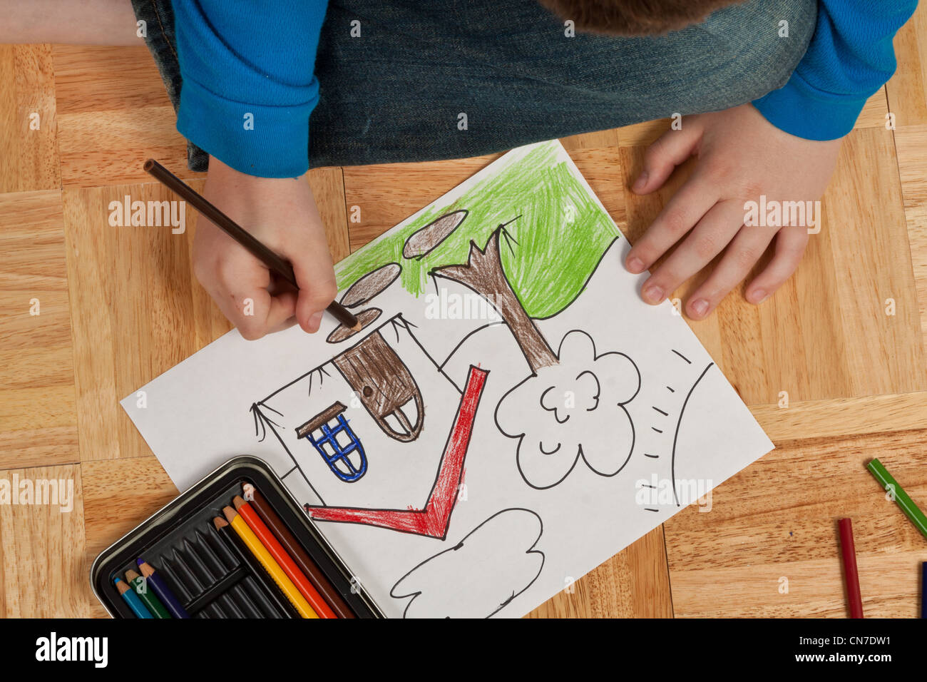 Young boy in blue shirt coloring a picture with pencils while laying on ...