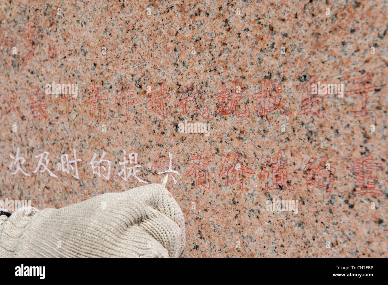 Beijing, Wanan cemetery. Hand of a man engraving a biography of a ...