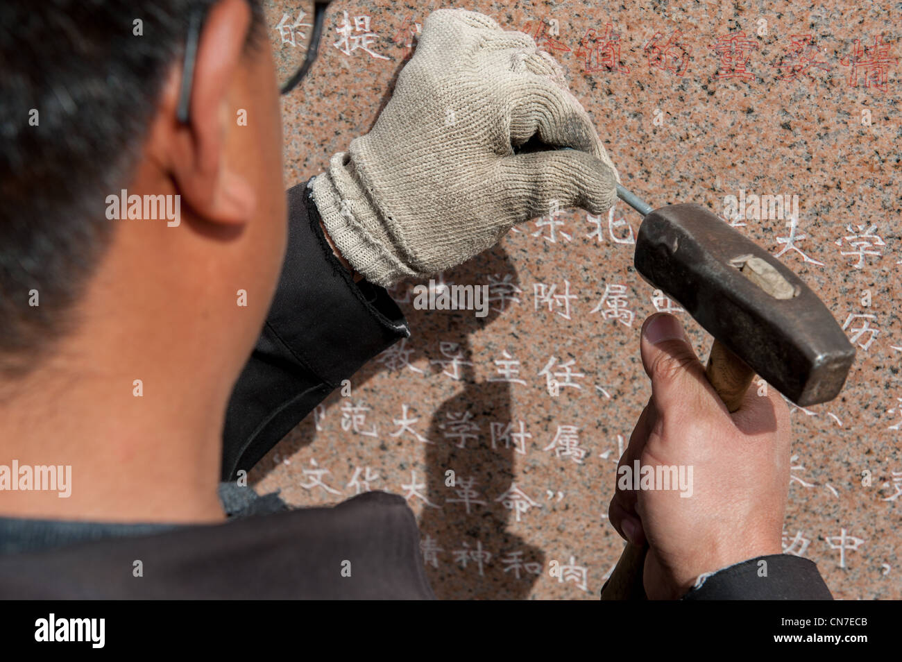 Beijing, Wanan cemetery. Hand of a man engraving a biography of a ...