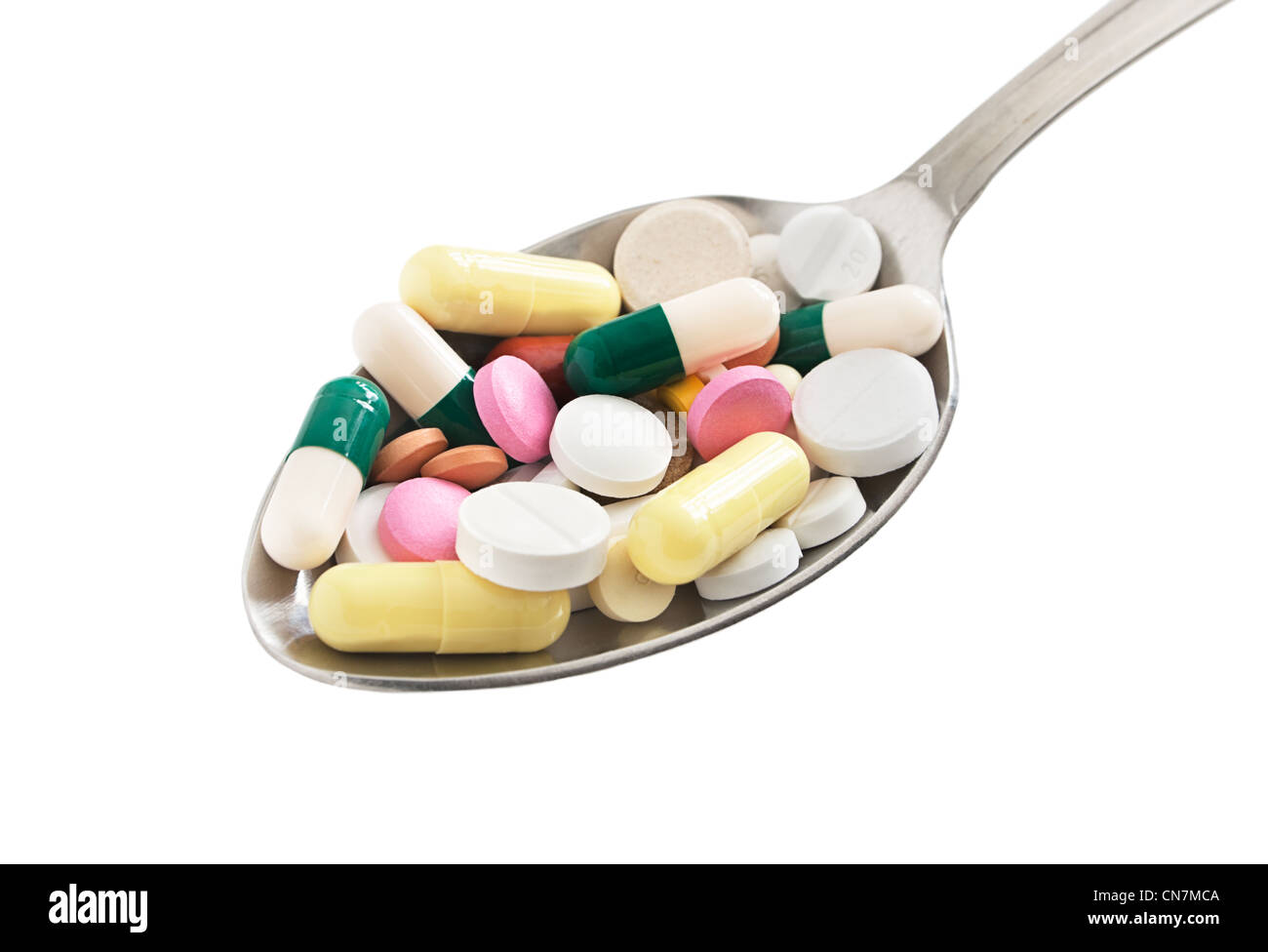 A large spoon with medical tablets and capsules isolated on white ...