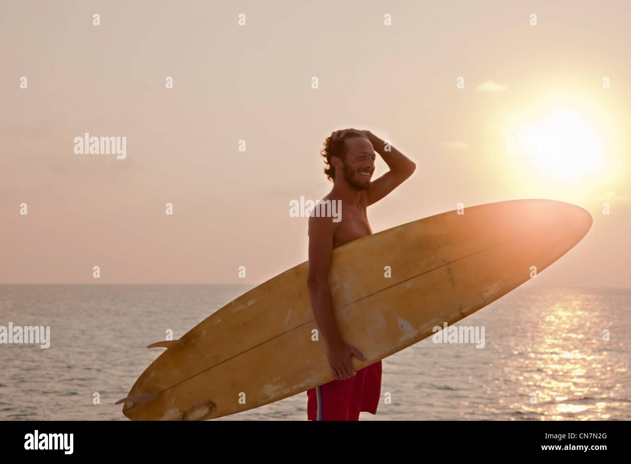 Surfer carrying board on beach Stock Photo - Alamy