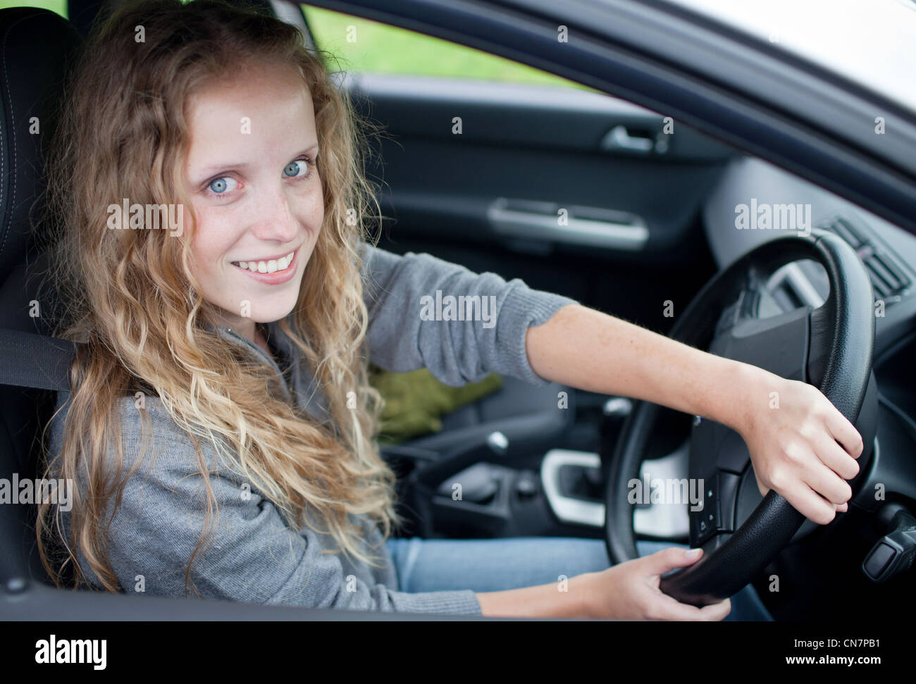 Pretty young woman driving her new car Stock Photo - Alamy