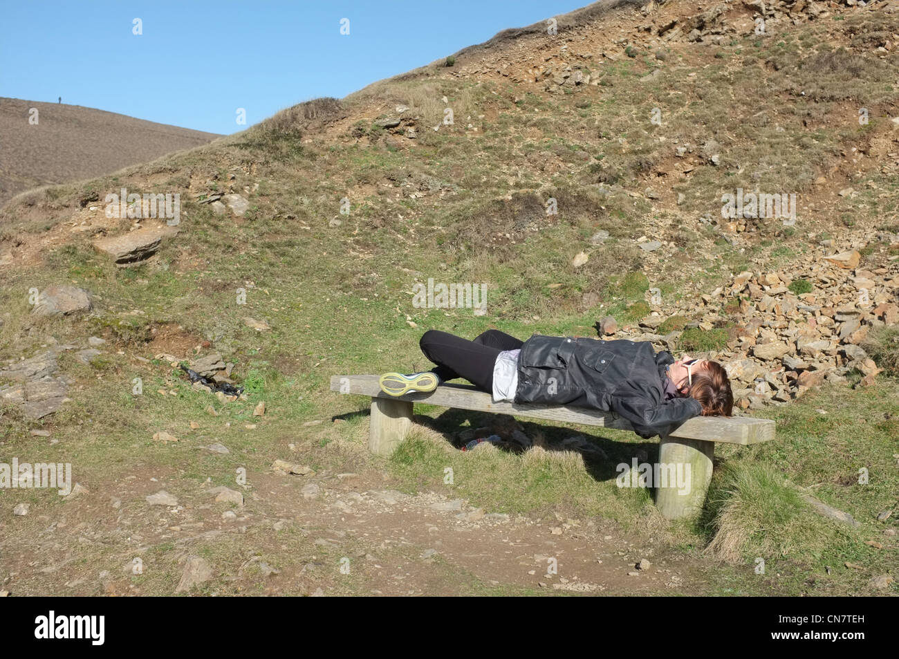 A female rambler takes a break in the winter sun of Cornwall to absorb ...