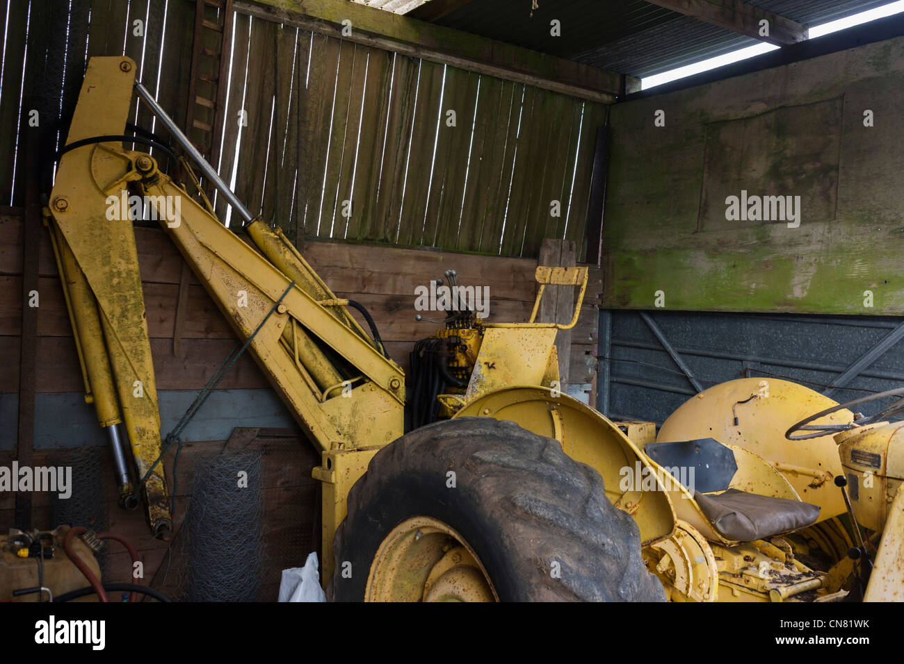 Yellow tractor stored undercover in a smallholding shed during spring ...
