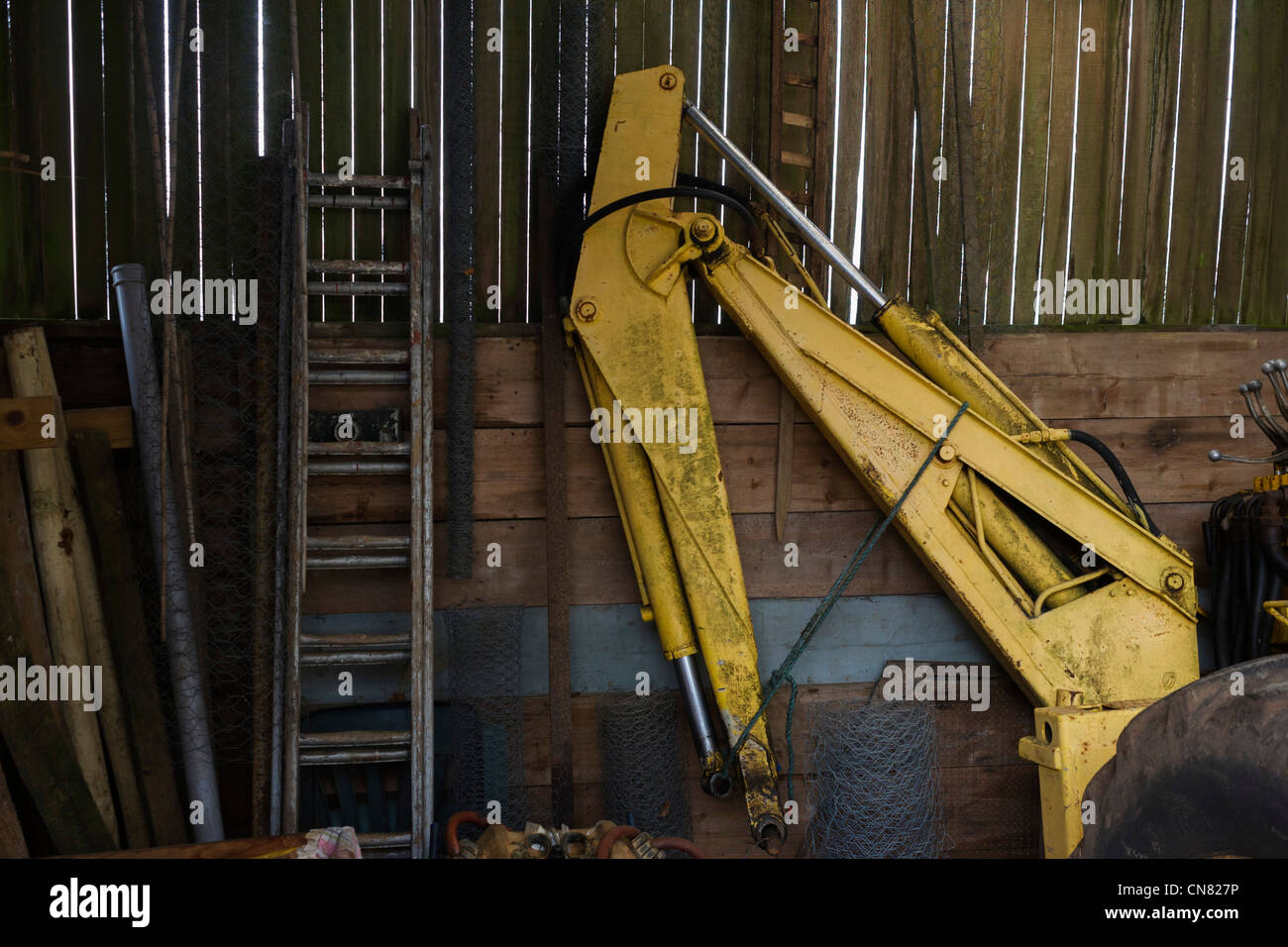 Yellow tractor stored undercover in a smallholding shed during spring ...