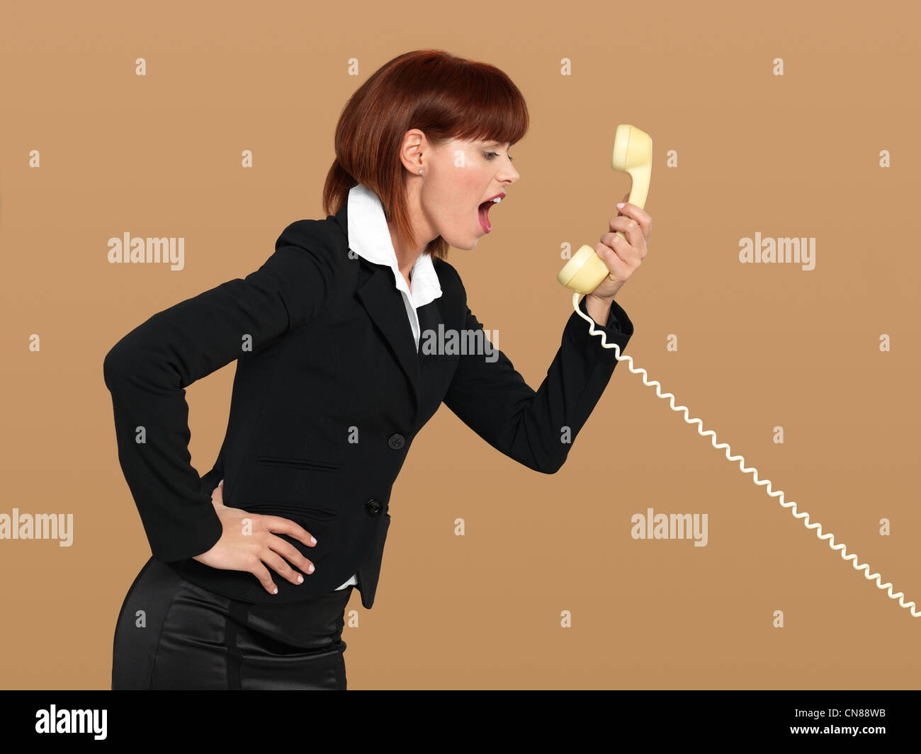 portrait of a stressed, young businesswoman, screaming to the telephone ...