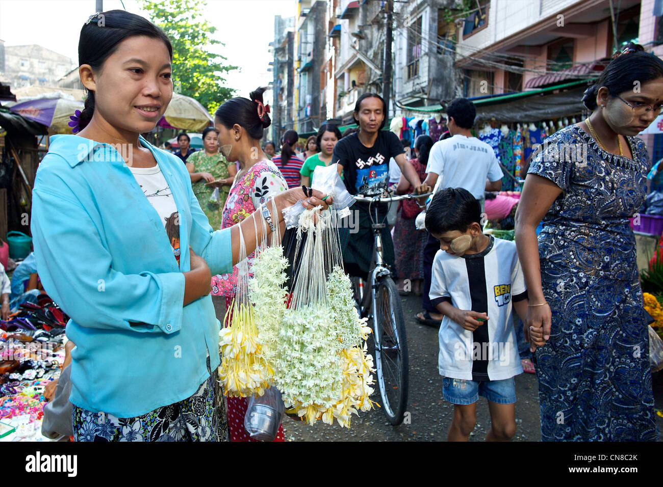 A young Burmese girl sells jasmine flower garlands in a street market on the streets of Yangon ...