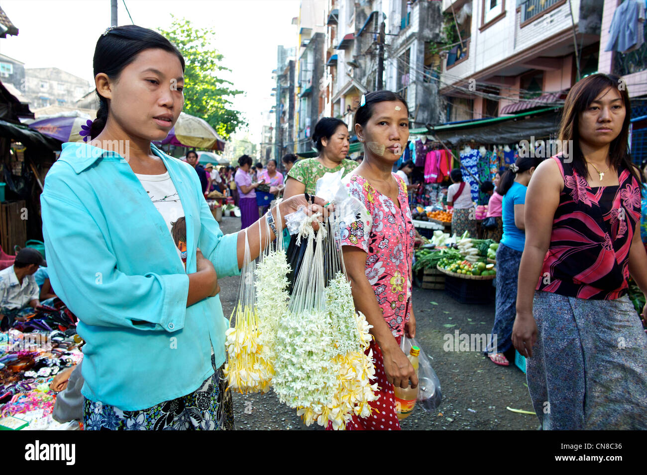 A young Burmese girl sells jasmine flower garlands in a street market on the streets of Yangon ...