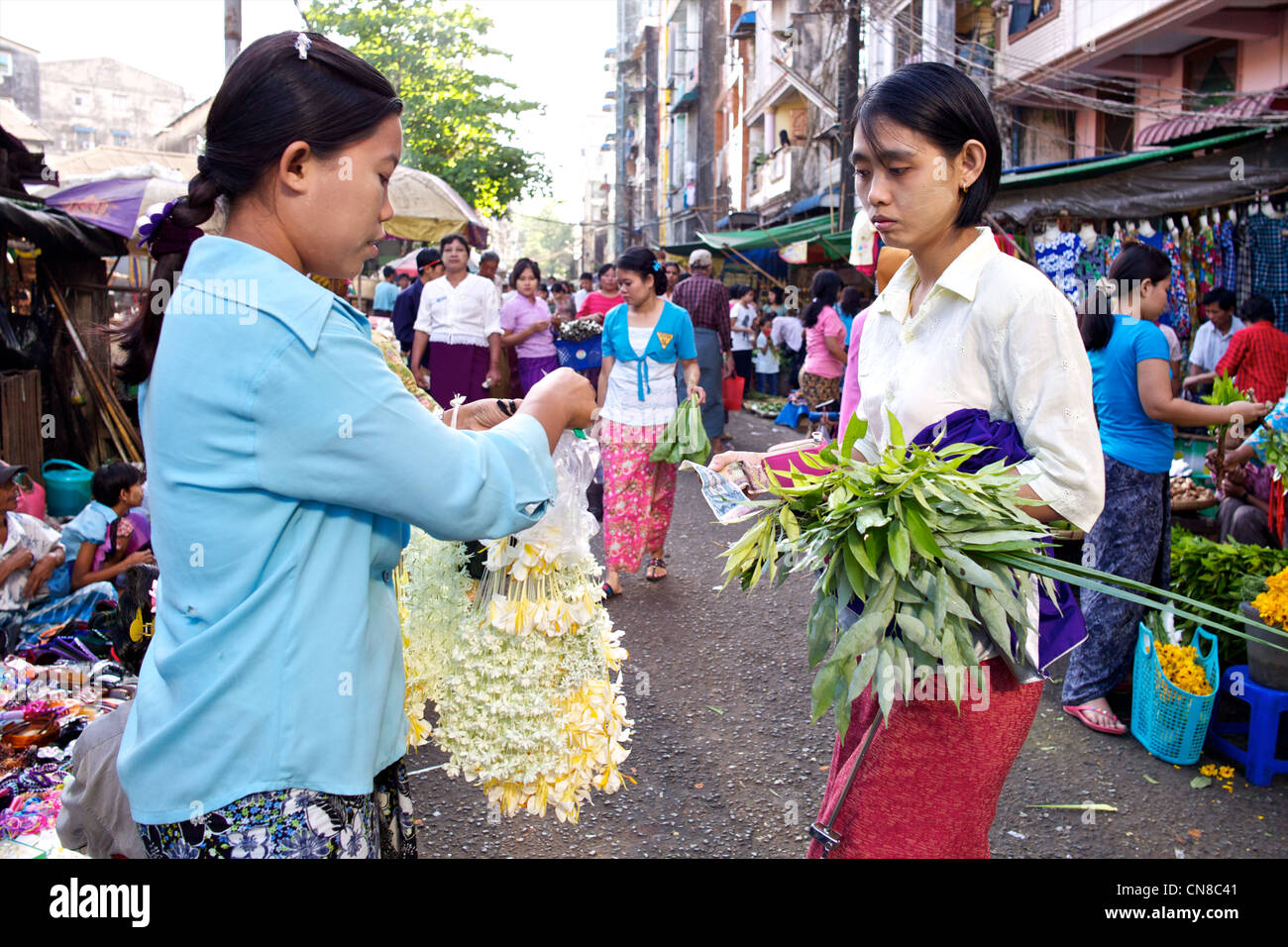 A young Burmese girl sells jasmine flower garlands in a street market on the streets of Yangon ...
