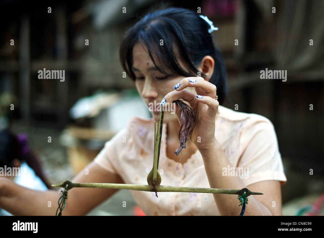 A Burmese woman uses a traditional set of scales in a street market on ...