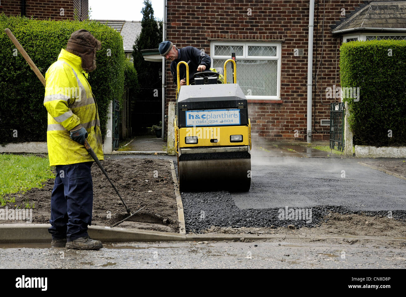 Small road roller smoothing fresh asphalt on new off road parking bay ...