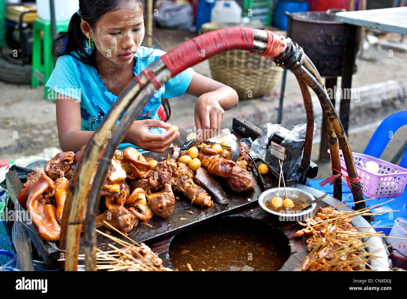 A young Burmese girl prepares street food on the streets of Yangon ...