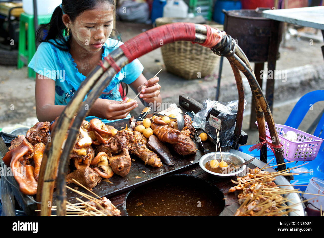 A young Burmese girl prepares street food on the streets of Yangon ...