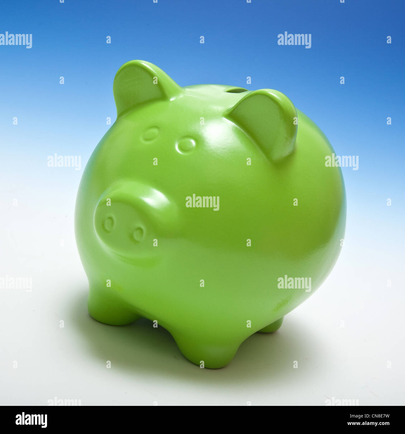 Green piggy bank or money box on a graduated blue studio background ...