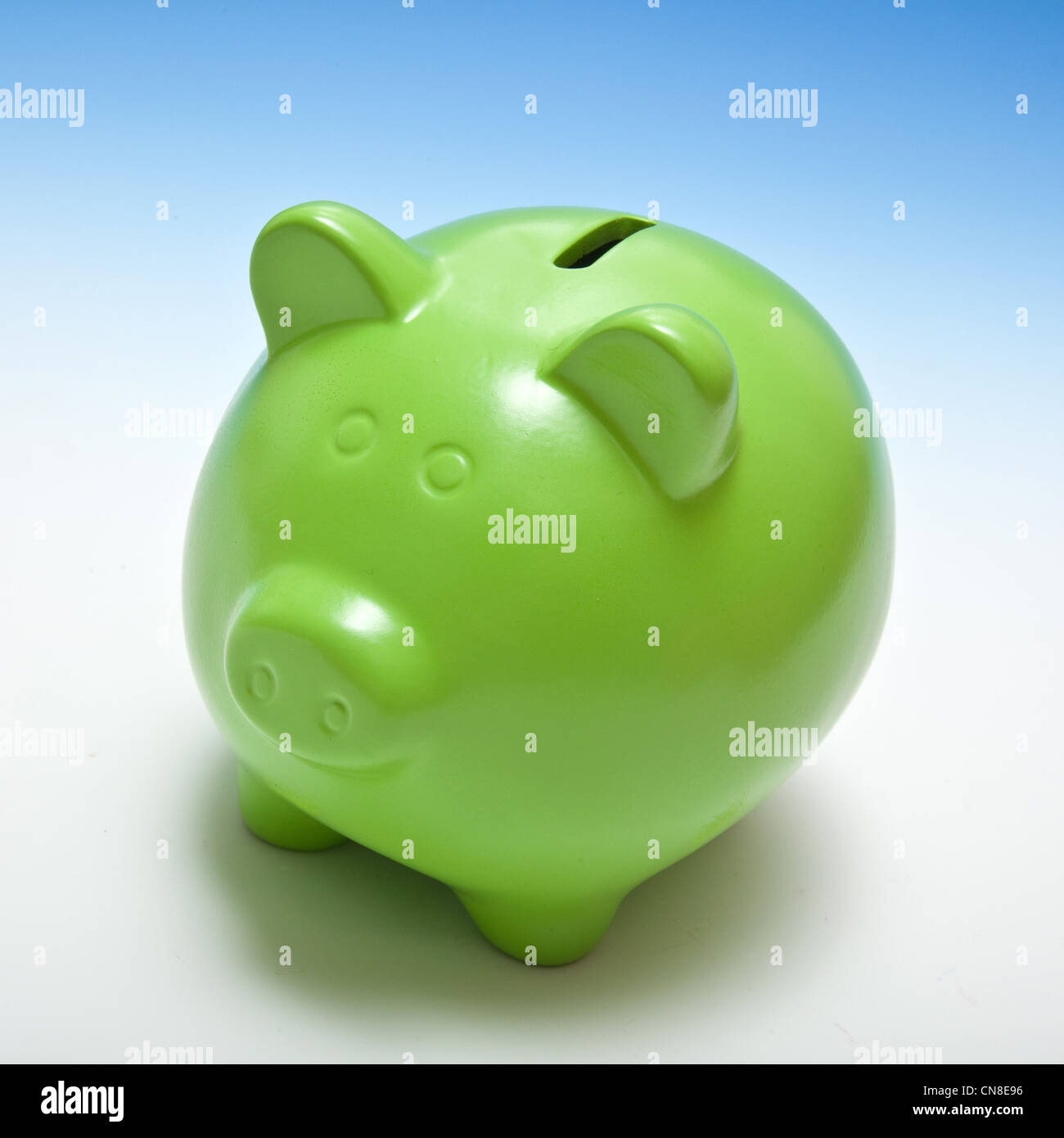 Green piggy bank or money box on a graduated blue studio background ...