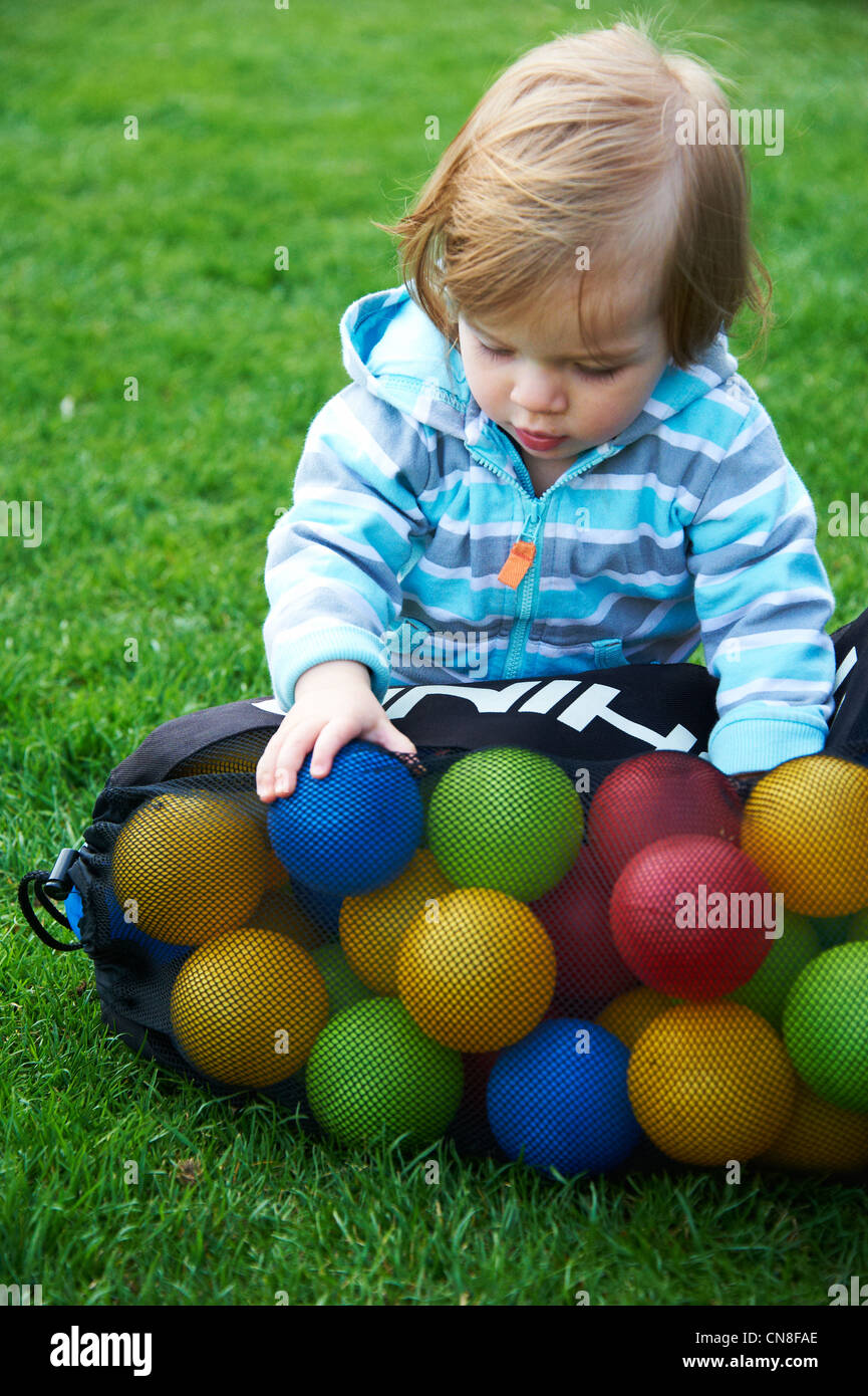 Child baby girl with bag of colorful balls Stock Photo - Alamy