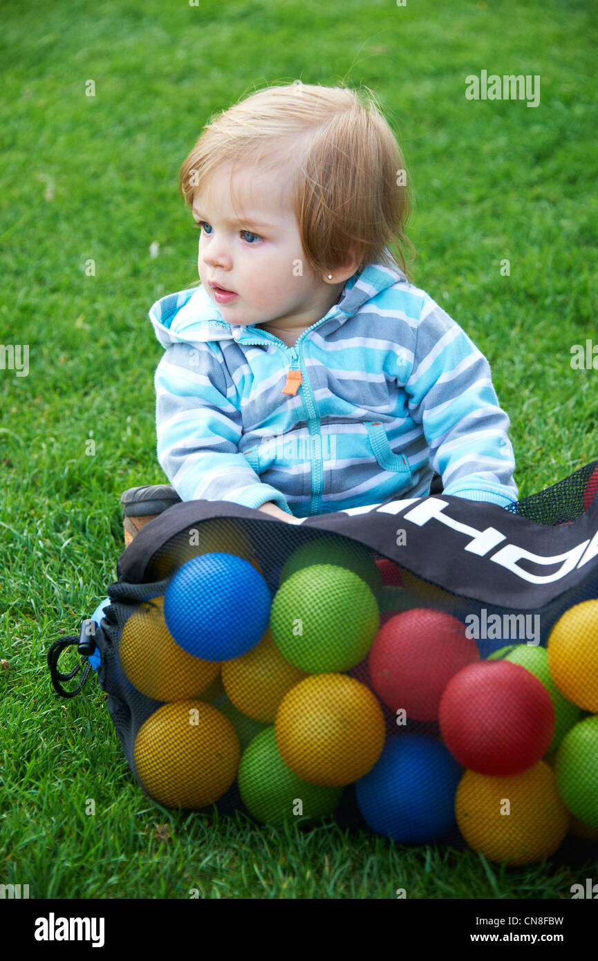 Child baby girl with bag of colorful balls Stock Photo - Alamy