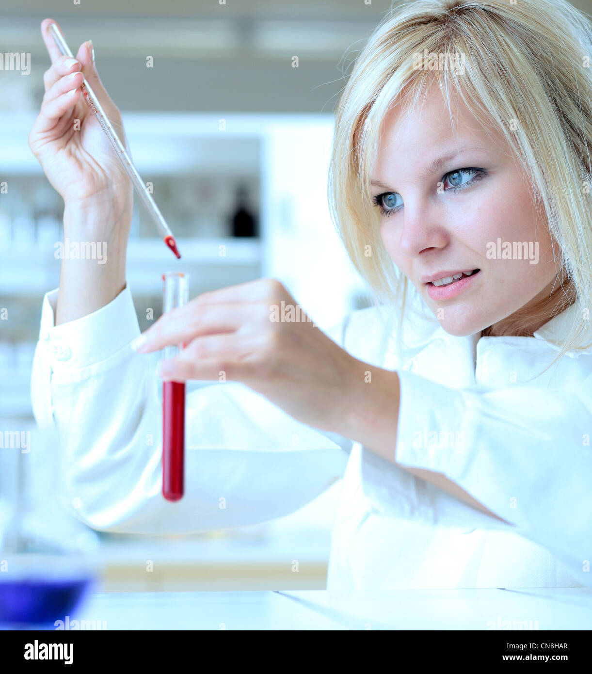 Closeup of a female researcher holding up a test tube and a retort and ...