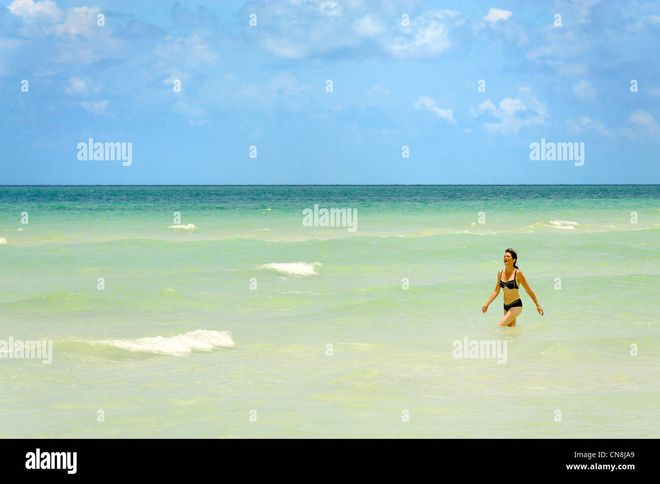 Bahamas, Grand Bahama Island, Freetown, young woman walking in water on ...