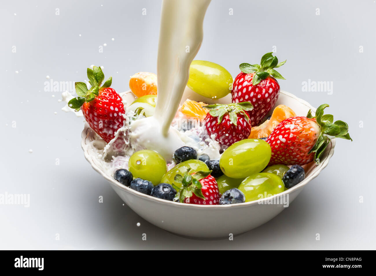Milk pouring into dish with fresh fruits Stock Photo - Alamy