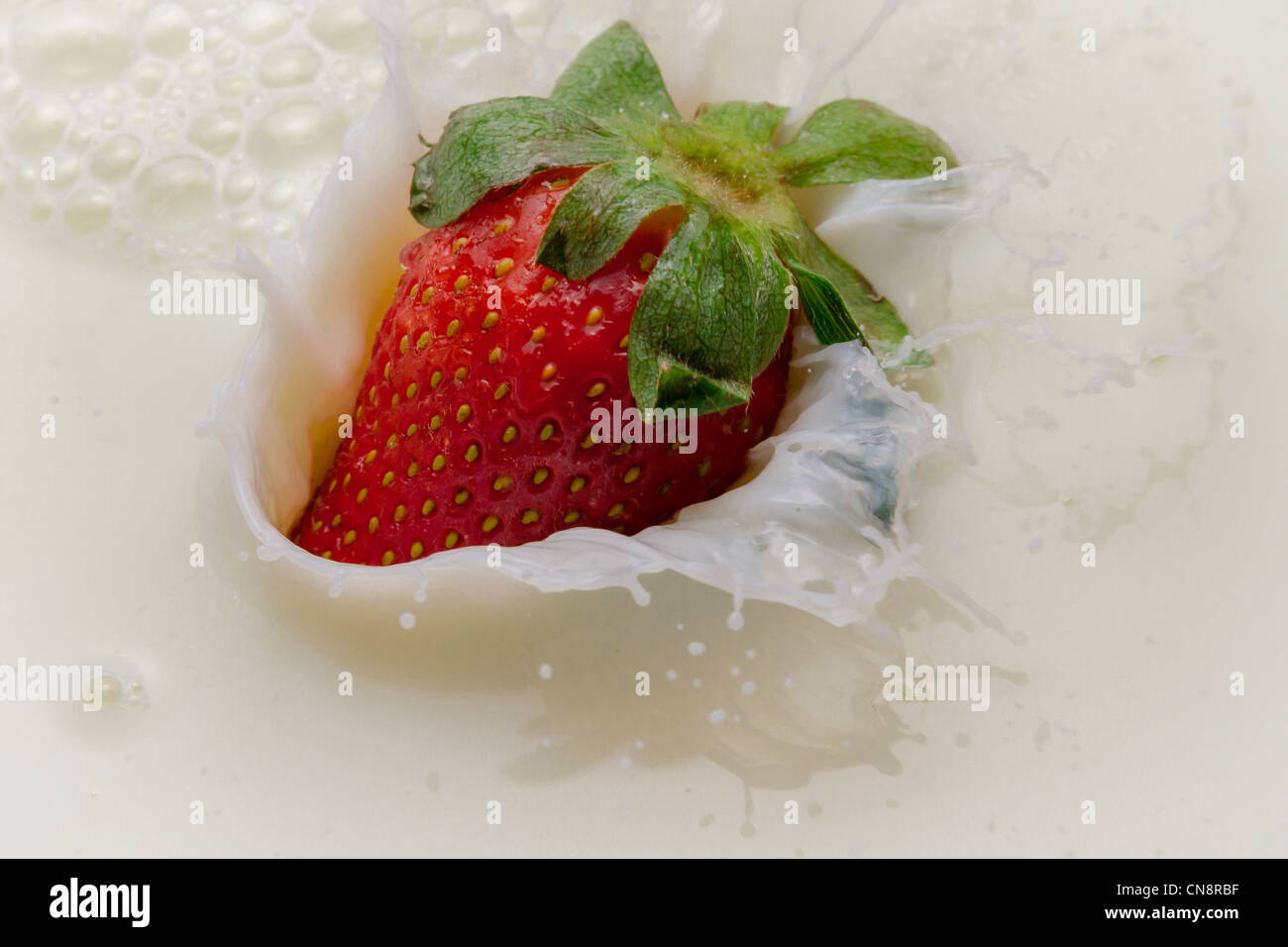 Strawberry falling into milk with a splash Stock Photo - Alamy
